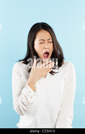 Asian woman are yawning covering open mouth with hand after she wake up ...