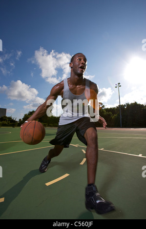 Young basketball player driving to the hoop for a high flying slam dunk ...