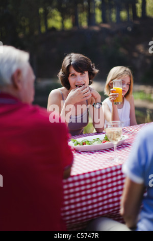 Granddaughter drinking orange juice sitting near granddad Stock Photo ...