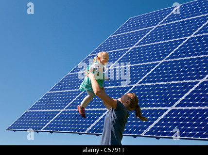 Smiling mother and daughter with sustainable energy generators at home ...