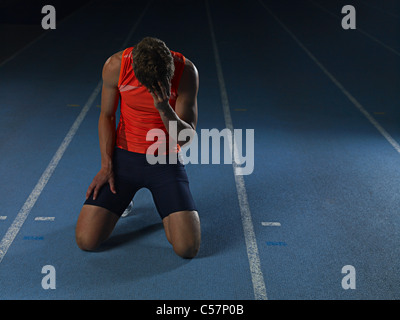 Front view of disappointed athlete crouching on grass Stock Photo - Alamy