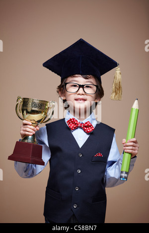 boy pick up the trophy wearing graduation cap Stock Photo - Alamy