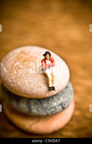Miniature woman sitting on a stone between lesser celandine (Ficaria ...
