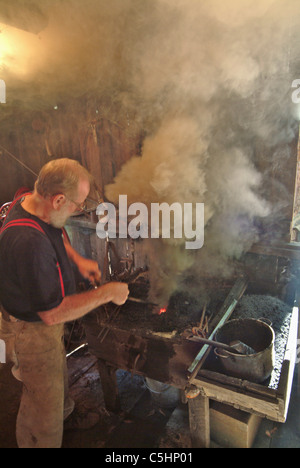 A blacksmith pumps more air into the coal fed fire to make it burn ...