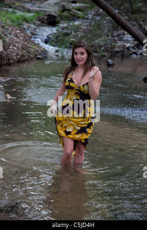 Lovely woman wading in a creek and looking at the camera Stock Photo ...