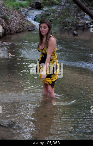 Lovely woman wading in a creek and looking at the camera Stock Photo ...