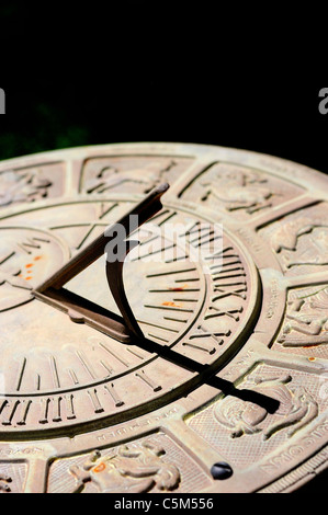 Sundial with Zodiac signs and figures surrounding Roman numeral times ...
