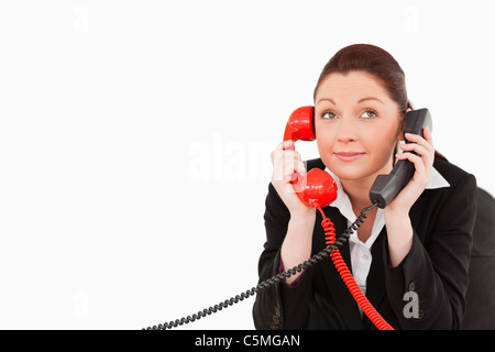 Cute secretary answering two phone calls at the same time against a ...