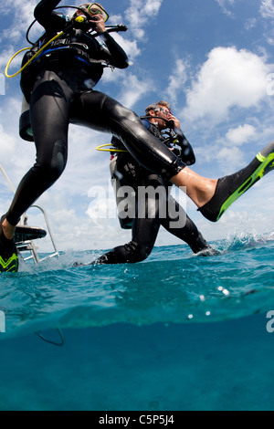 MALE DIVER DOES GIANT STRIDE ENTRY FROM BOAT INTO WATER IN THE CAYMAN ...