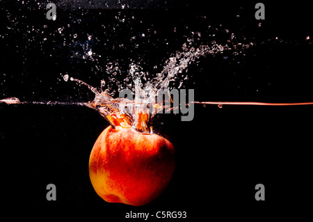 Apple dropped into water on a black background Stock Photo - Alamy