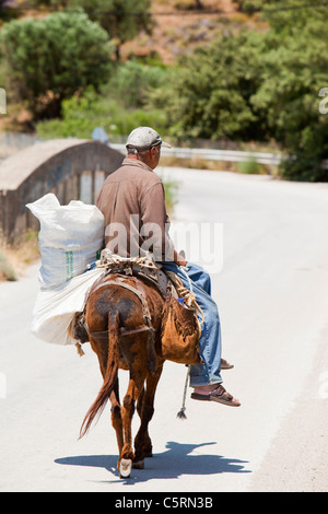 An old Greek farmer using a traditional form of transport, the donkey ...