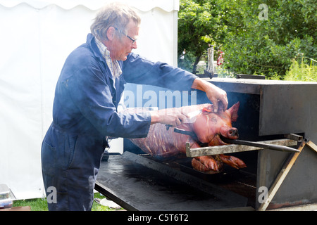 Cutting and carving spit-roasted whole pig hog, on a Midwestern farm ...