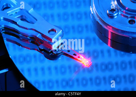 Computer hard drive, opened, writing/reading head and hard disk. Binary code numbers are ...