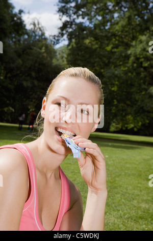 Young woman eating tasty cereal rings on lilac background Stock Photo ...
