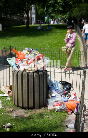 Overflow bin in London park with rubbish left around the filled up bin ...