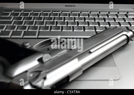 a silver gun on a Macbook pro laptop , conceptual image , metaphor ...