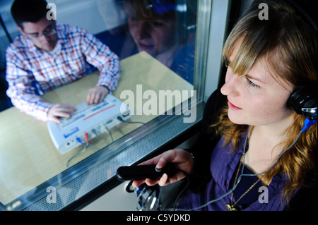 Audiology and deafness sound booth with young female 18-20 wearing ...