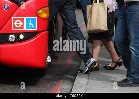 legs of people boarding a red London bus at a bus stop in London Stock ...