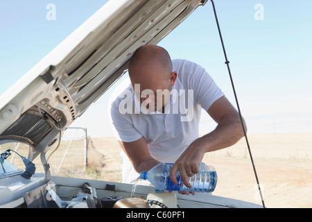 Pouring water on car engine. Washing car engine with spray, brush and ...