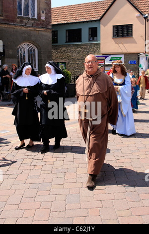 Medieval monk in period clothes pouring beer into mug from kettle ...