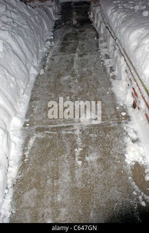 A sidewalk cleared of deep snow, with a clear path carved through the ...