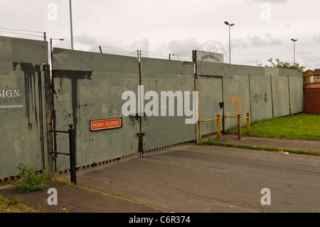 Closed gate across a road at one of the Belfast "Peace Walls", covered ...