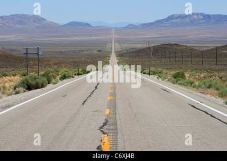 A straight two lane highway stretches through a remote desert canyon ...