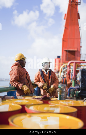 Worker leaning on railing of oil rig Stock Photo - Alamy