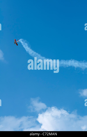 Blue aerobatic plane doing a loop the loop roll and leaving a large ...