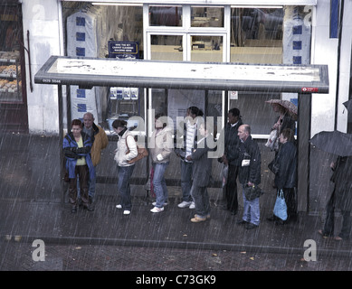 People queue in the rain for a bus on a wet Tuesday morning at the ...