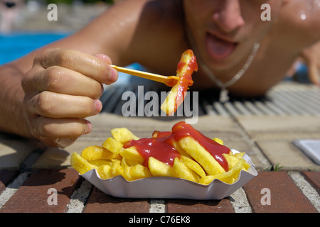 A bather in a swimming pool reaching for French fries Stock Photo - Alamy