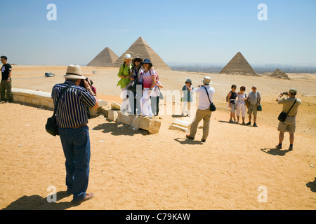 Tourists photograph one another with the Pyramids of the Giza Plateau ...