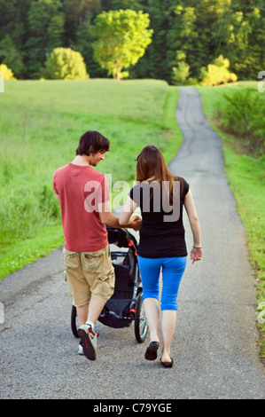 A young family with a baby in a stroller admire a view of a river while ...