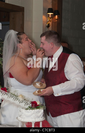 Bride and groom eating and feeding each other cake at wedding reception ...