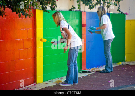 Volunteers paint decorations in a city playground during a community ...