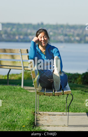 Asian young women sitting relaxed on sofa with headphones holding ...