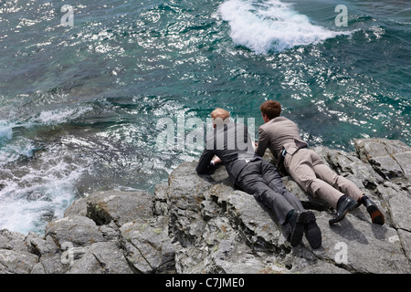 Businessmen peering over cliff edge Stock Photo - Alamy