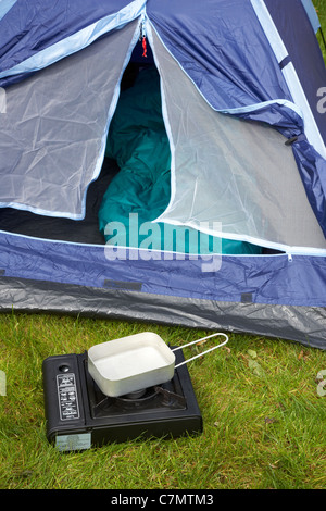 boiling water in a mess tin on a gas camping stove in front of a tent ...