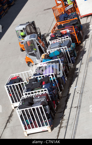 Baggage handlers loading cases on to conveyor belt to be loaded onto ...