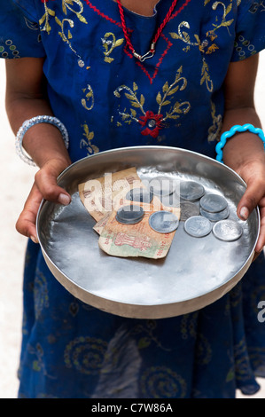 Indian street girl begging for money with rupee coins in her hand.Black ...