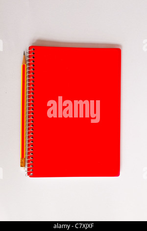 Notebook with a red pencil on a brown background with warm sunlight ...
