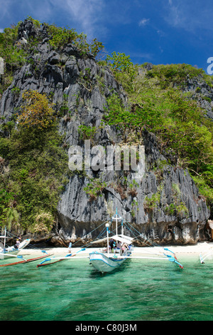 PHILIPPINES, Palawan, El Nido, Entalula Island, a woman takes a rest on ...
