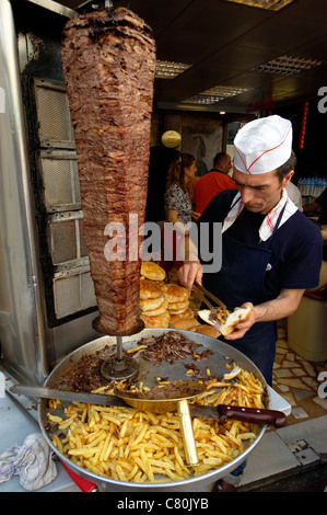 Turkish food, doner. Worker cooking preparing the meat, roasted slowly ...