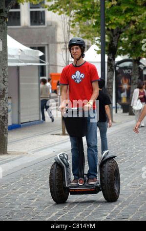 A young man riding Segway scooter on city street inspired rear view ...
