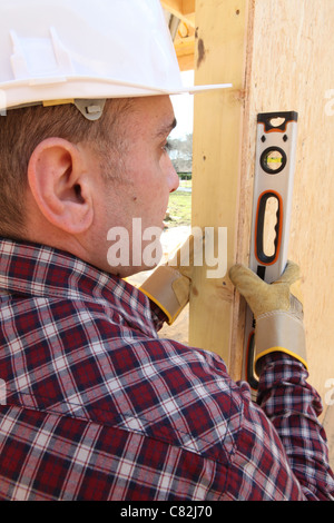Builder is using a spirit level to check new red brick wall made of red ...