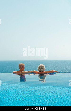 Couple relaxing in infinity pool Stock Photo - Alamy