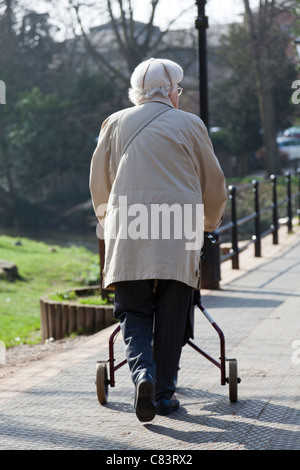 Elderly woman using a 3 wheeled walking frame Stock Photo - Alamy