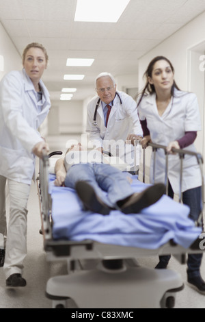 Doctors running Patient on gurney through hospital corridor, motion ...