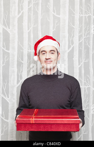 Smiling man in santa hat holding credit card near shopping cart with ...