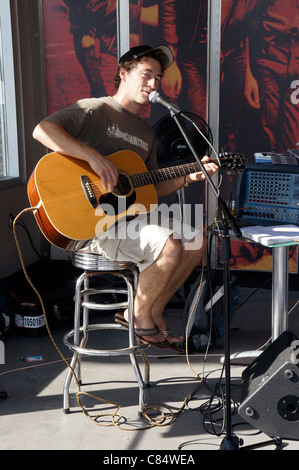 Young man playing on a guitar. Yellow and orange musical instrument ...
